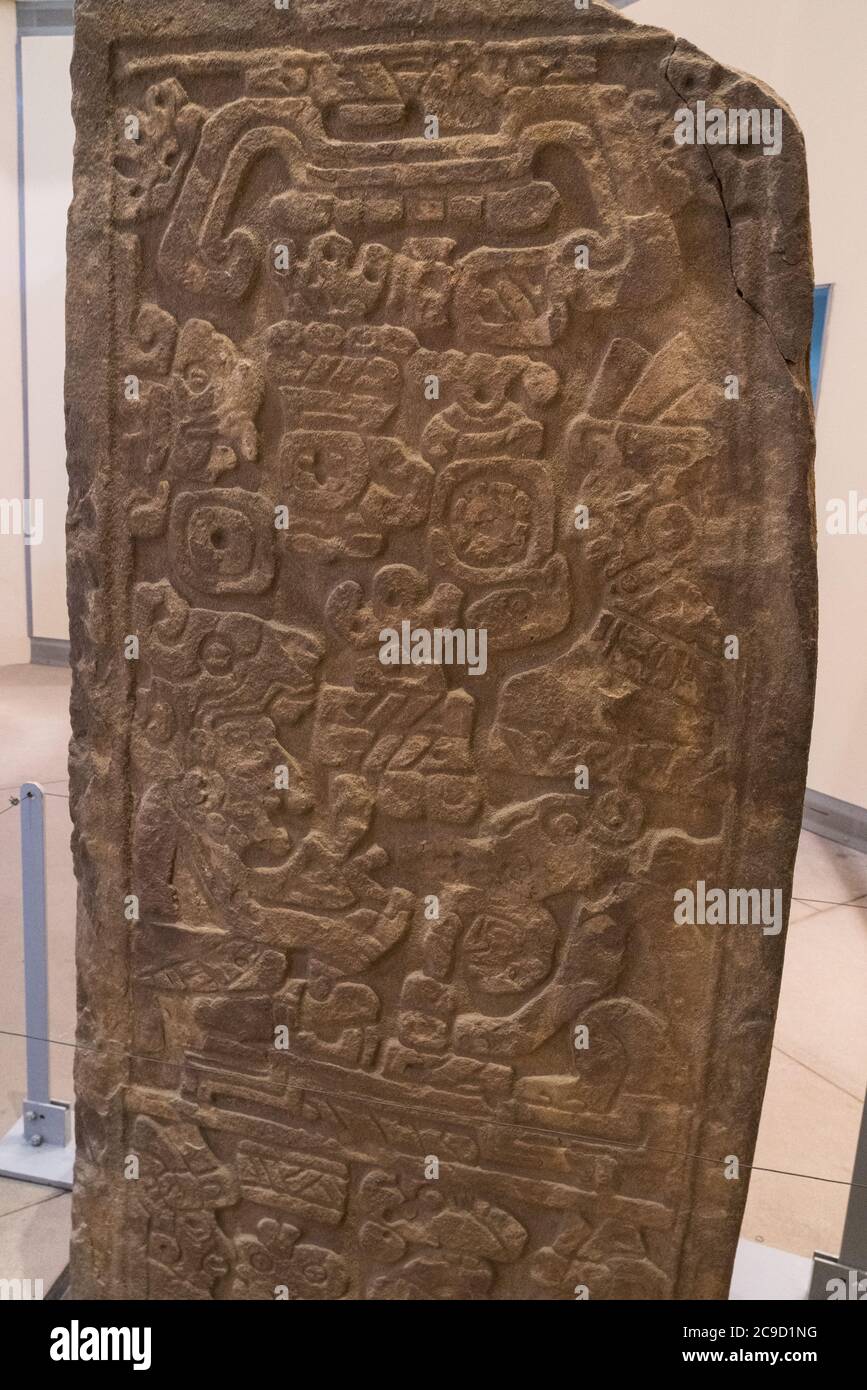 A carved stone stela from Monte Alban depicting a seated man facing a ...