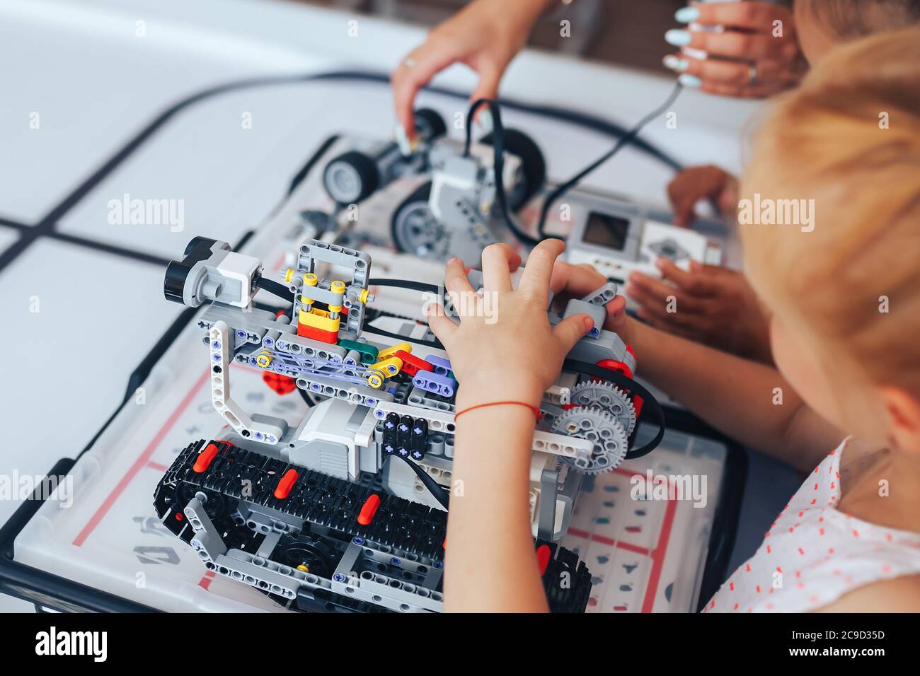 Two schoolgirls study in a robotics class, assemble a robot constructor ...