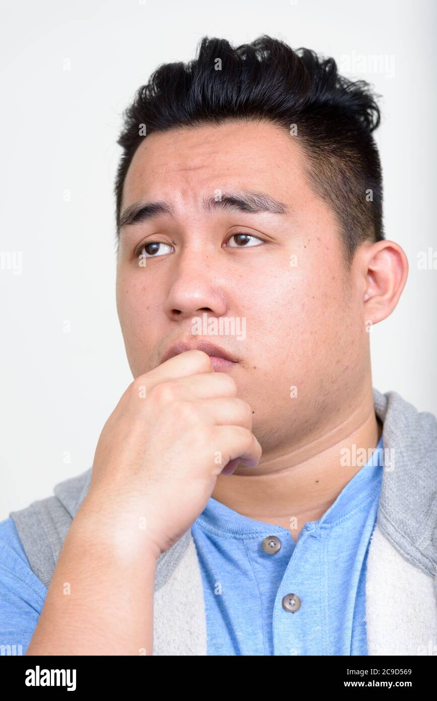 Portrait of stressed young overweight Asian man thinking Stock Photo ...