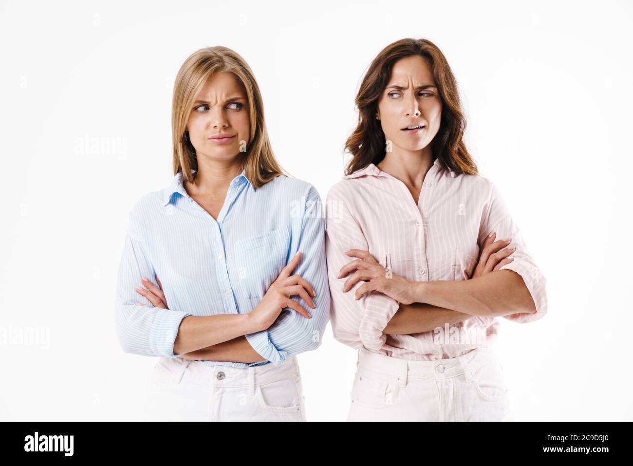 Image of resentful two women looking at each other while posing with ...