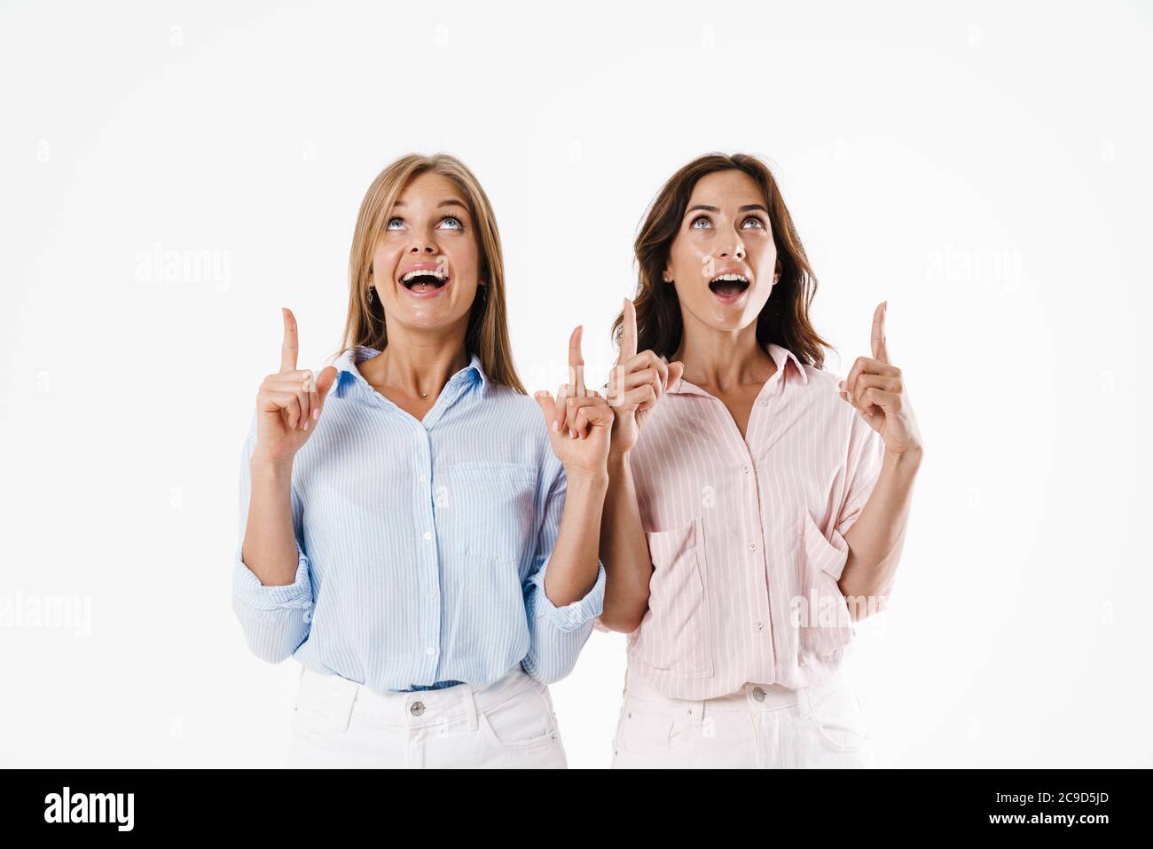 Image of excited beautiful two women pointing fingers upward isolated ...