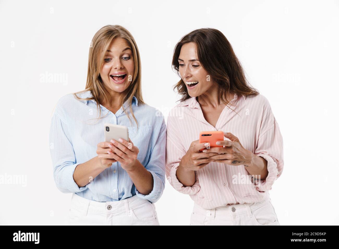 Image of beautiful excited two women using mobile phones isolated over ...