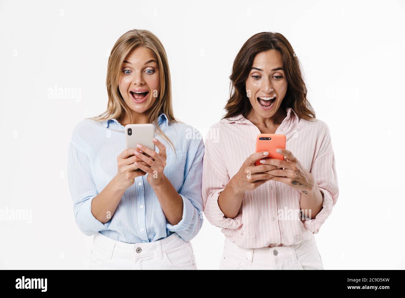 Image of excited two women expressing surprise while using mobile ...