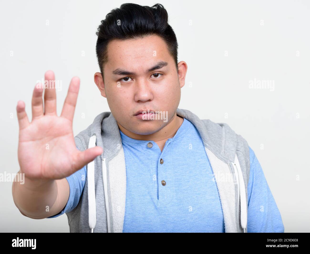 Portrait of stressed young overweight Asian man with stop gesture Stock ...