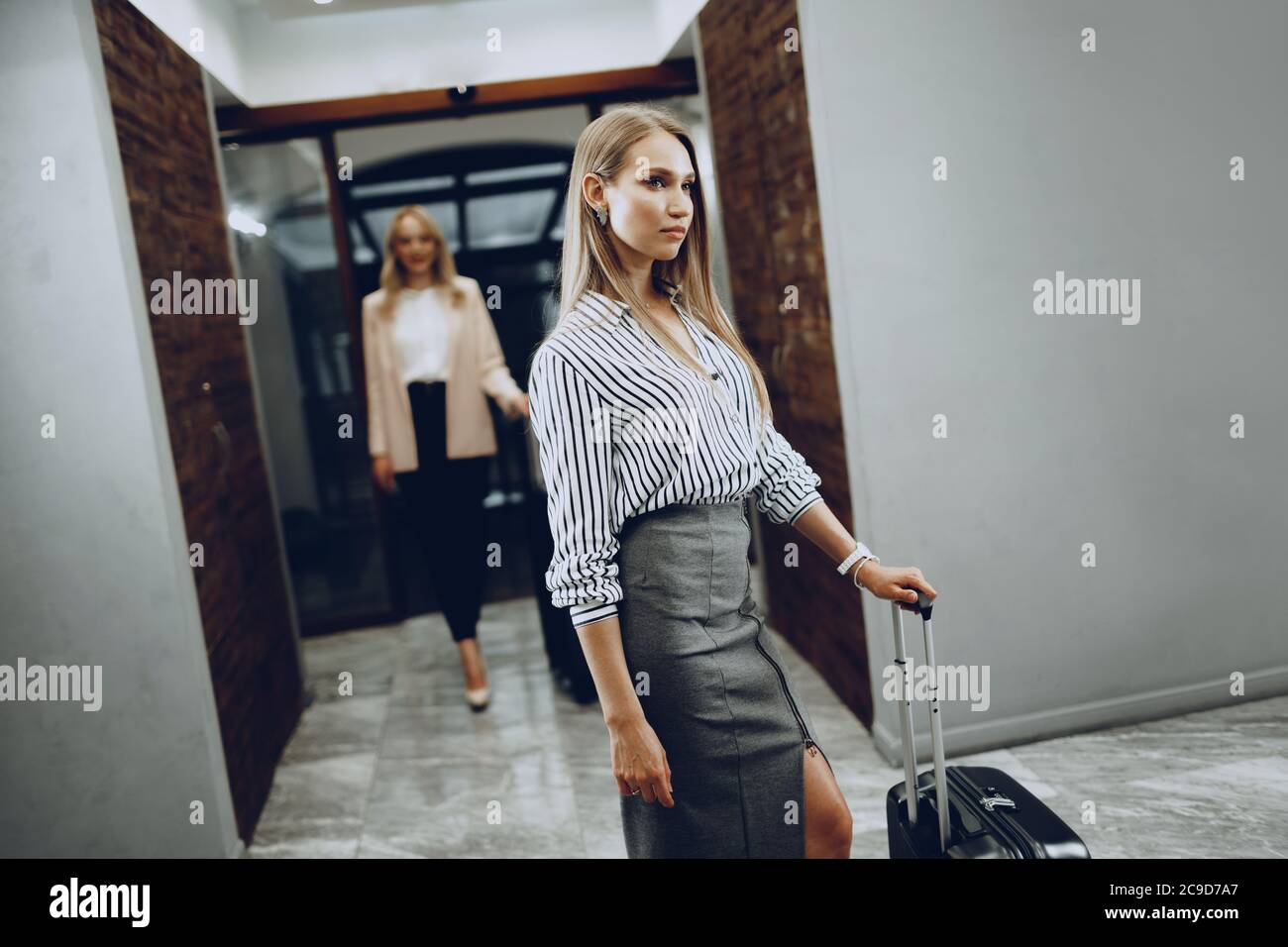 Two young women in formal clothes entering hotel lobby Stock Photo - Alamy
