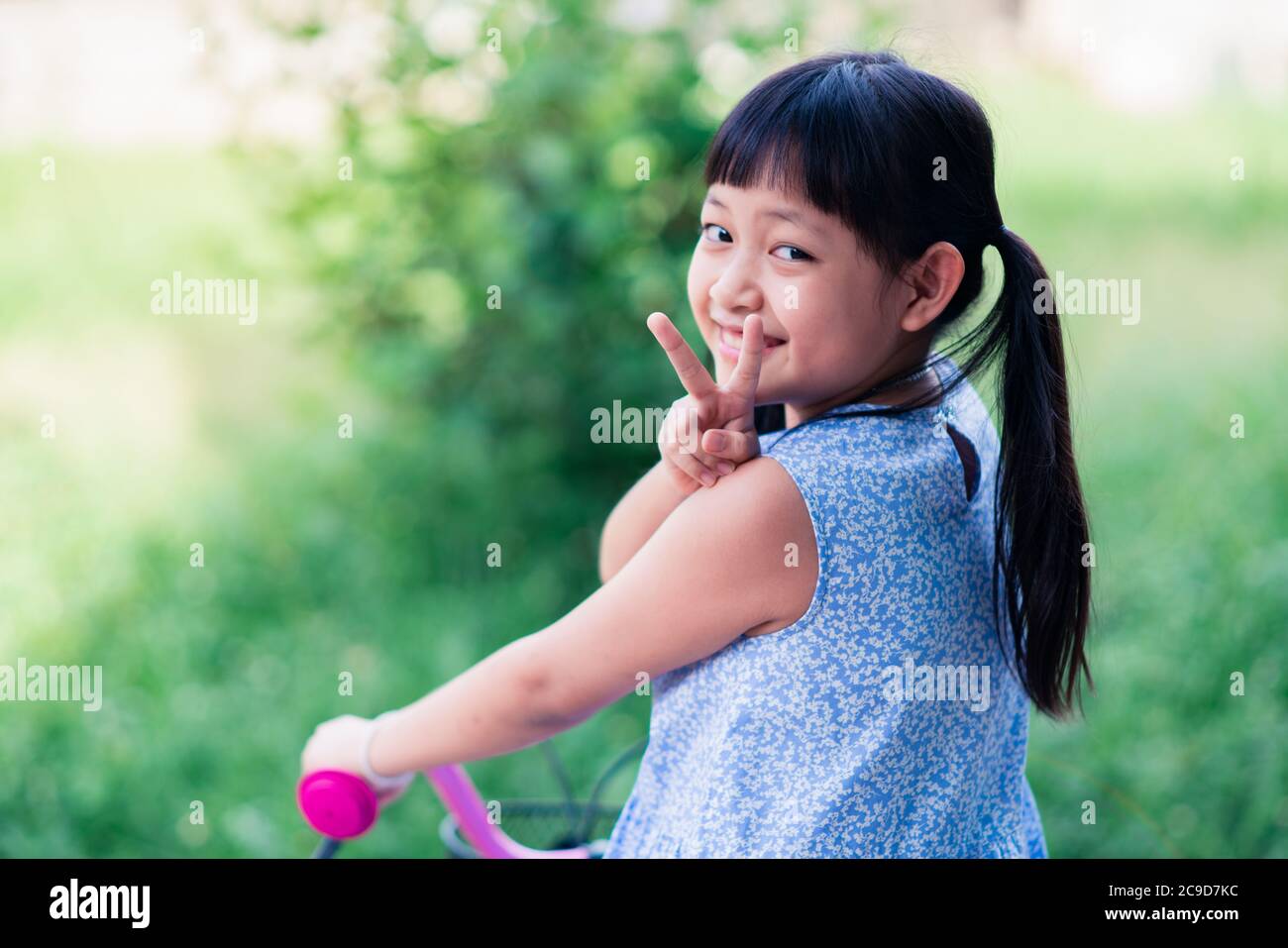 Asian little girl riding her bicycle outside with smile and happy Stock ...