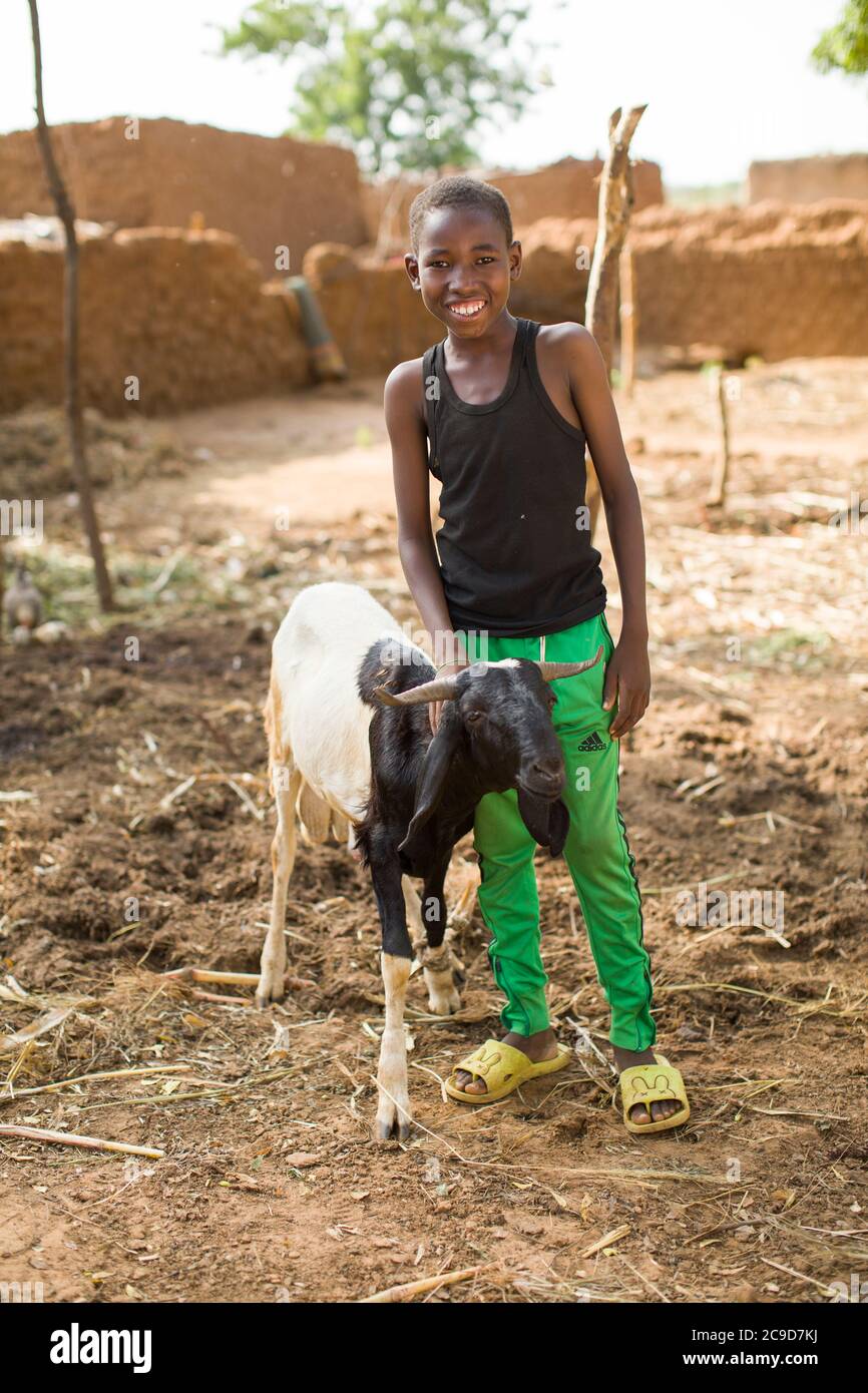 Child holding a sheep in a traditional African village in Tahoua Region ...