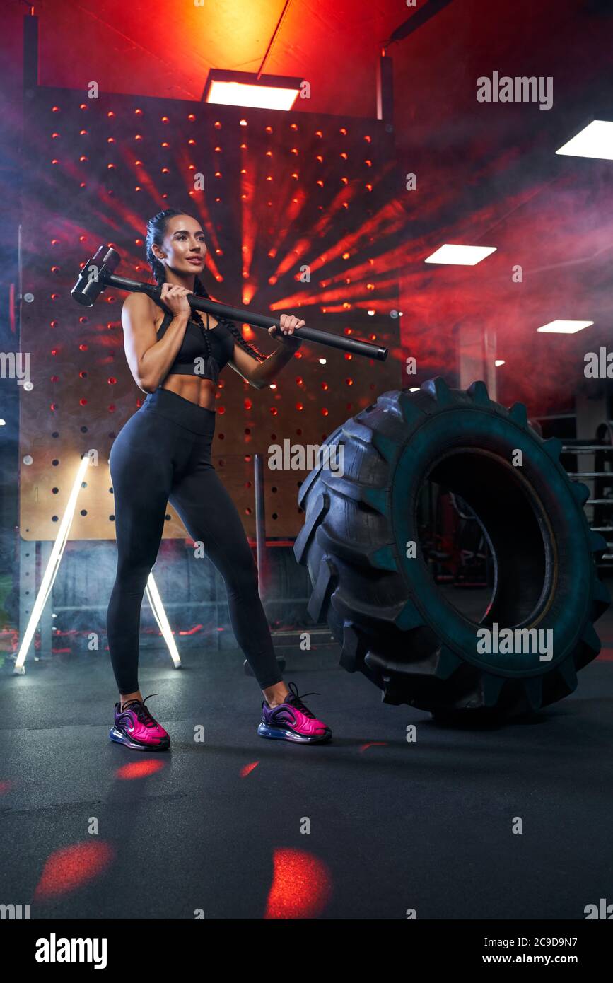 Front view of smiling female bodybuilder posing in gym, having rest ...