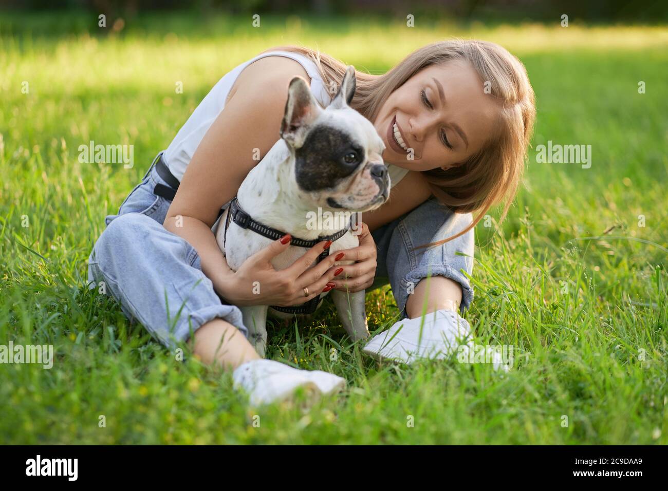 Close up view of young woman hugging adult french bulldog in summer ...
