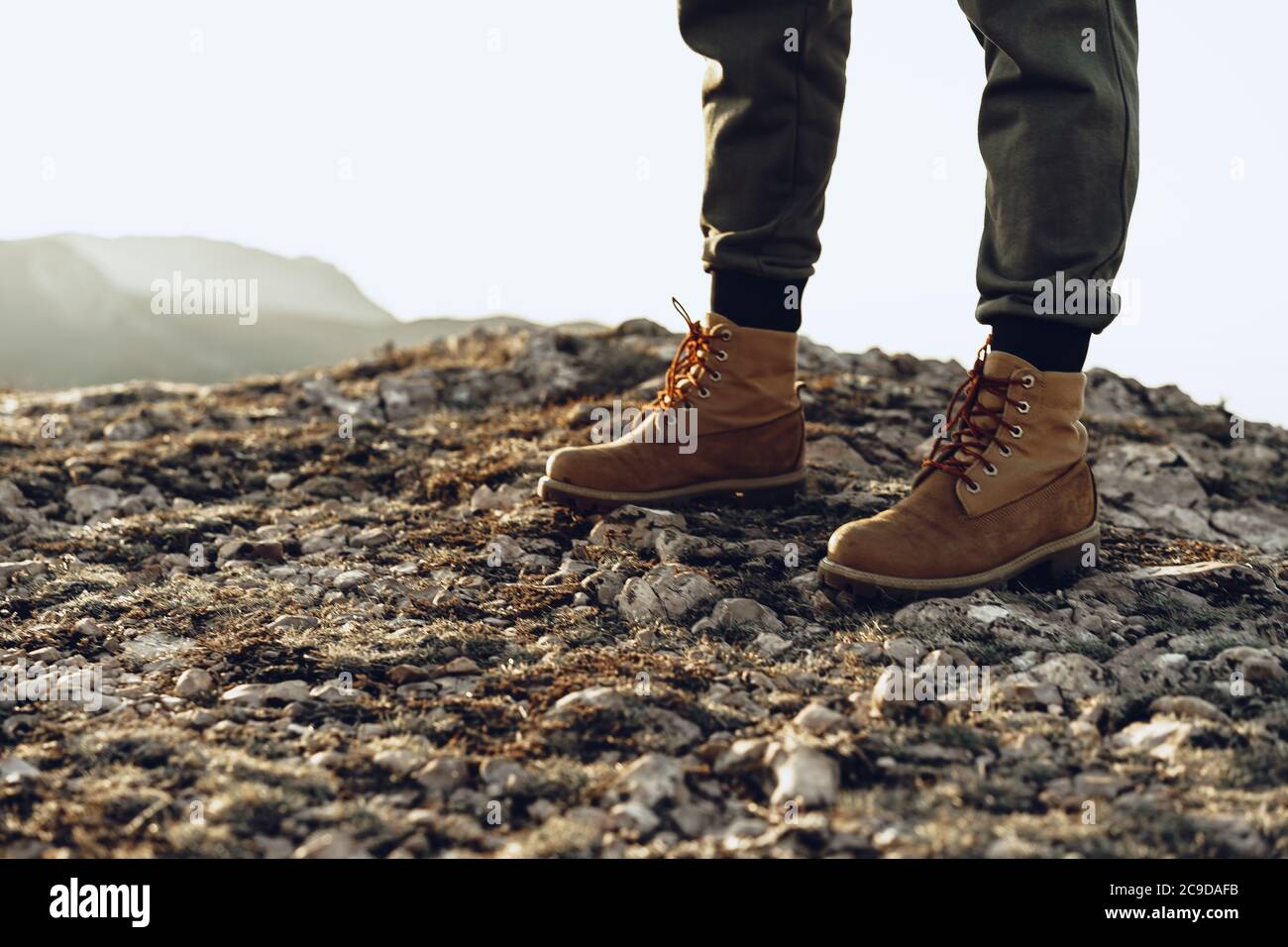 Legs of a backpacker in hiking boots standing on the top of the ...