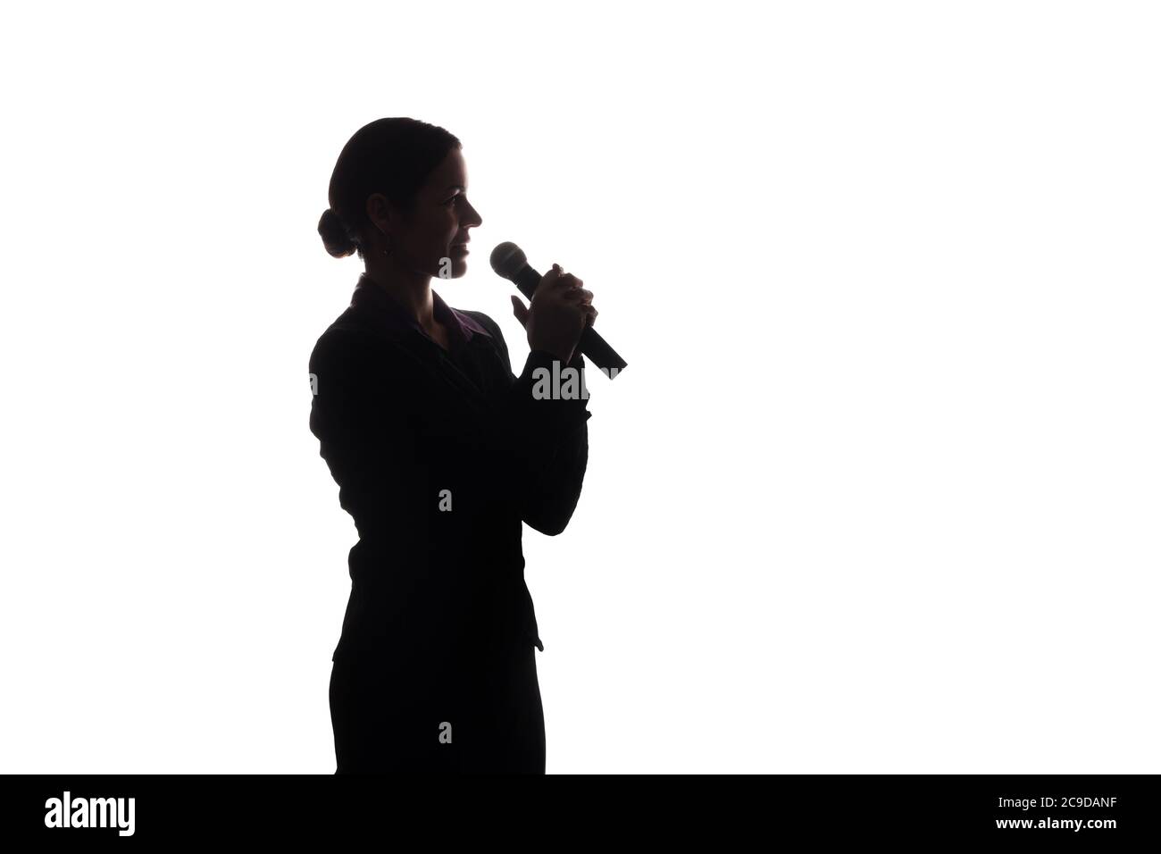 Young woman singing into the microphone, raising his hands - silhouette ...