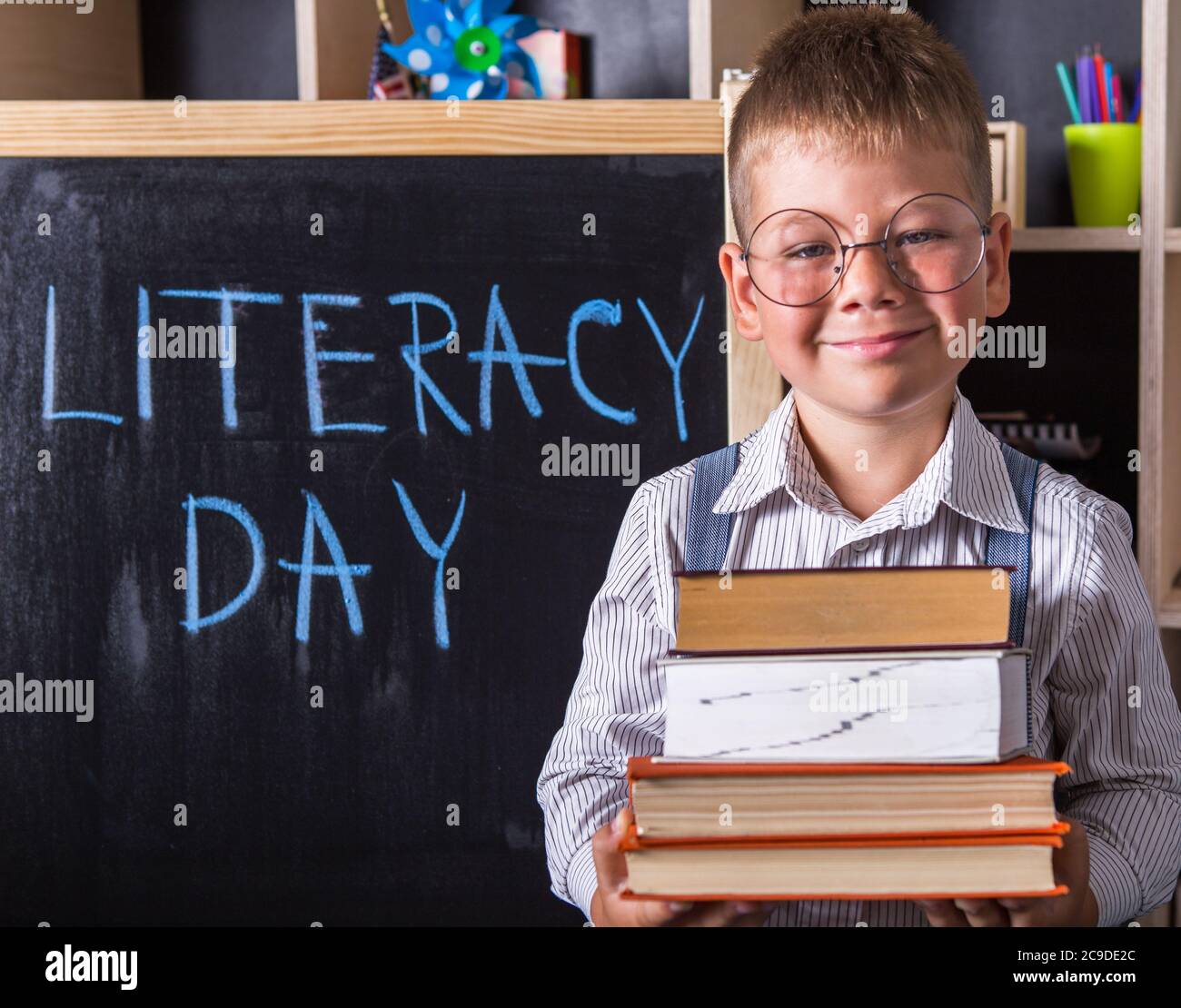 Portrait of cute little boy holding book in classroom. Happy ...
