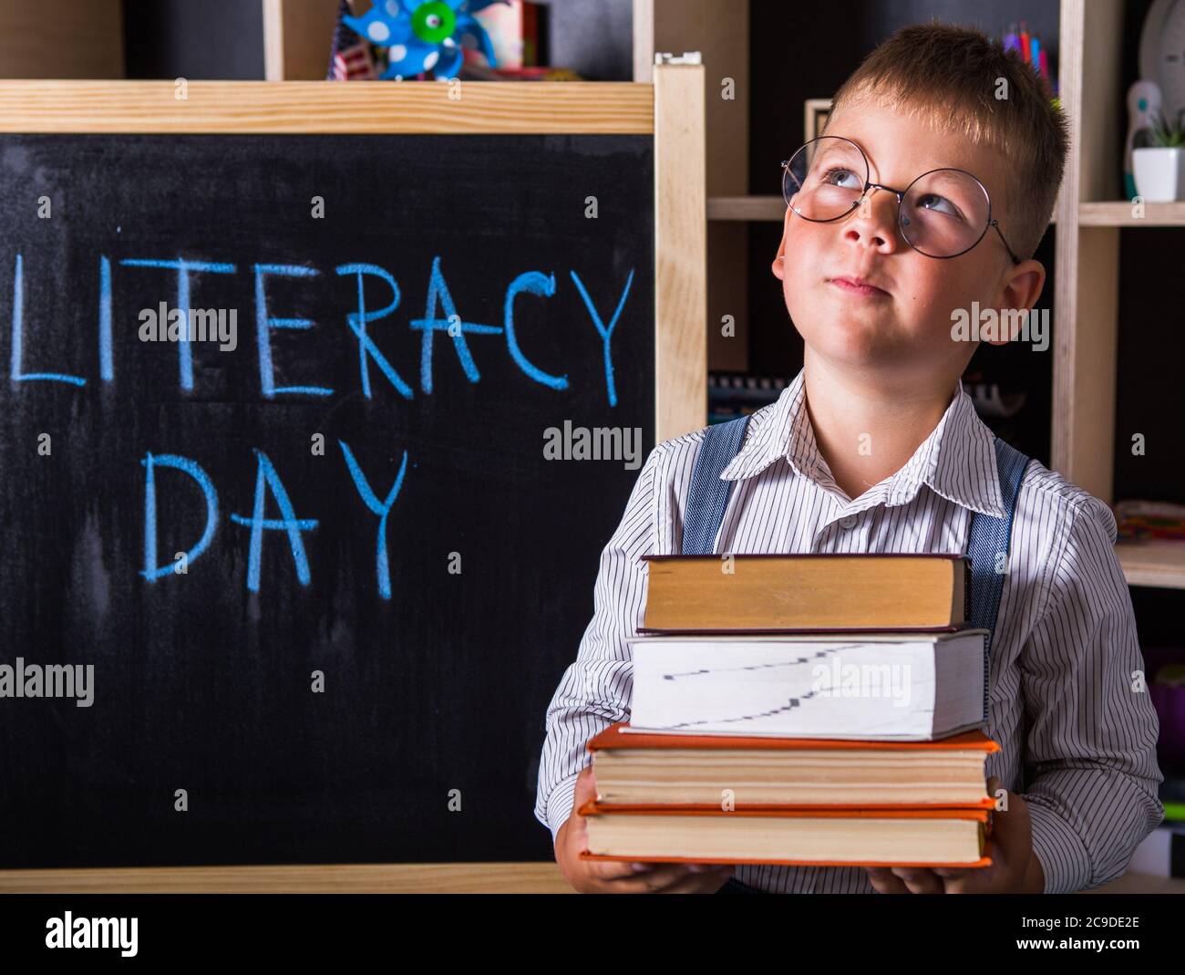 Portrait of cute little boy holding book in classroom. Happy ...
