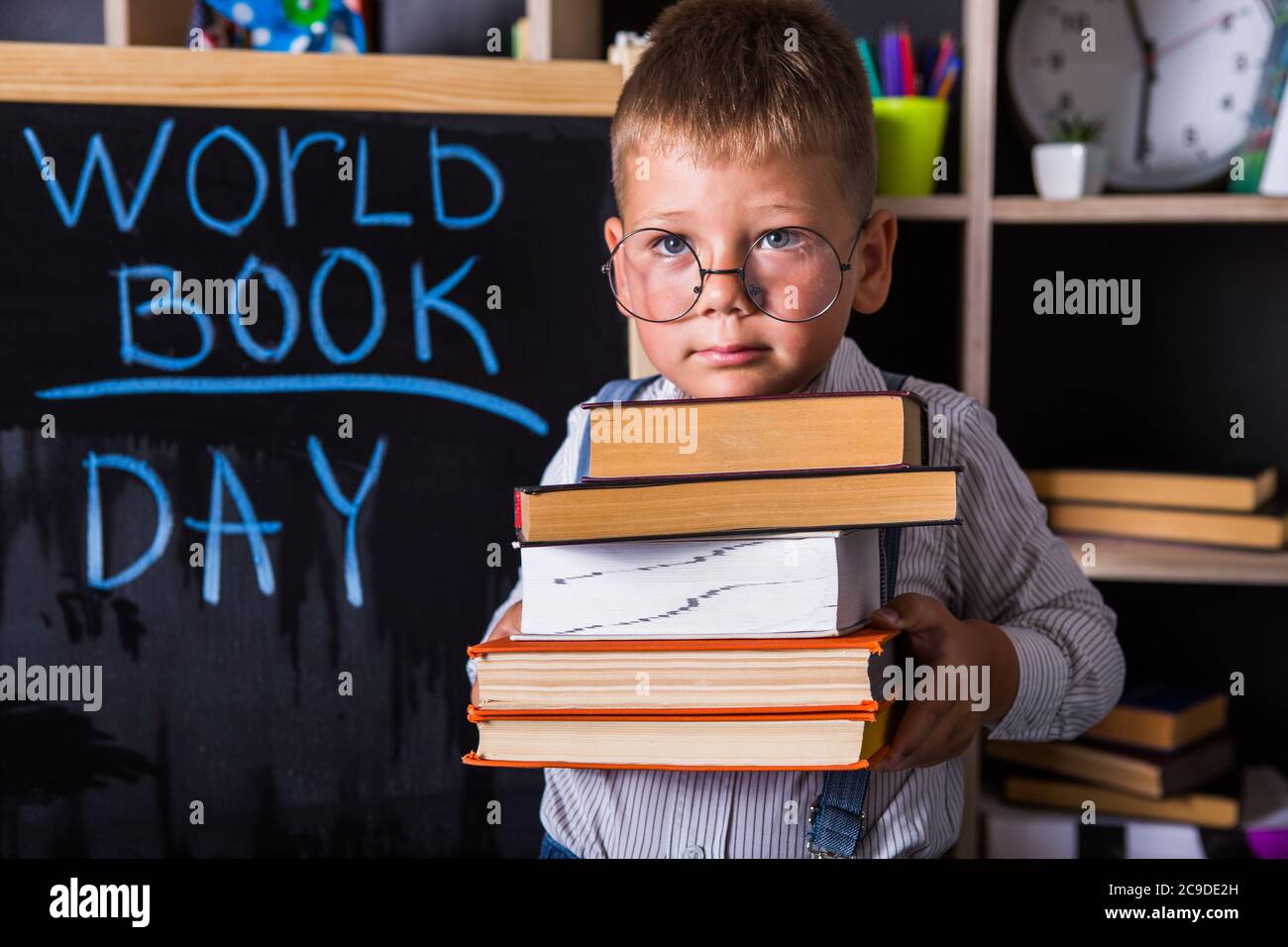 Portrait of cute little boy holding book in classroom. Happy ...