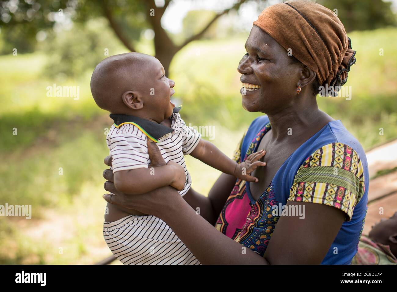 An African mother smiles at her baby boy he smiles back. Burkina Faso ...