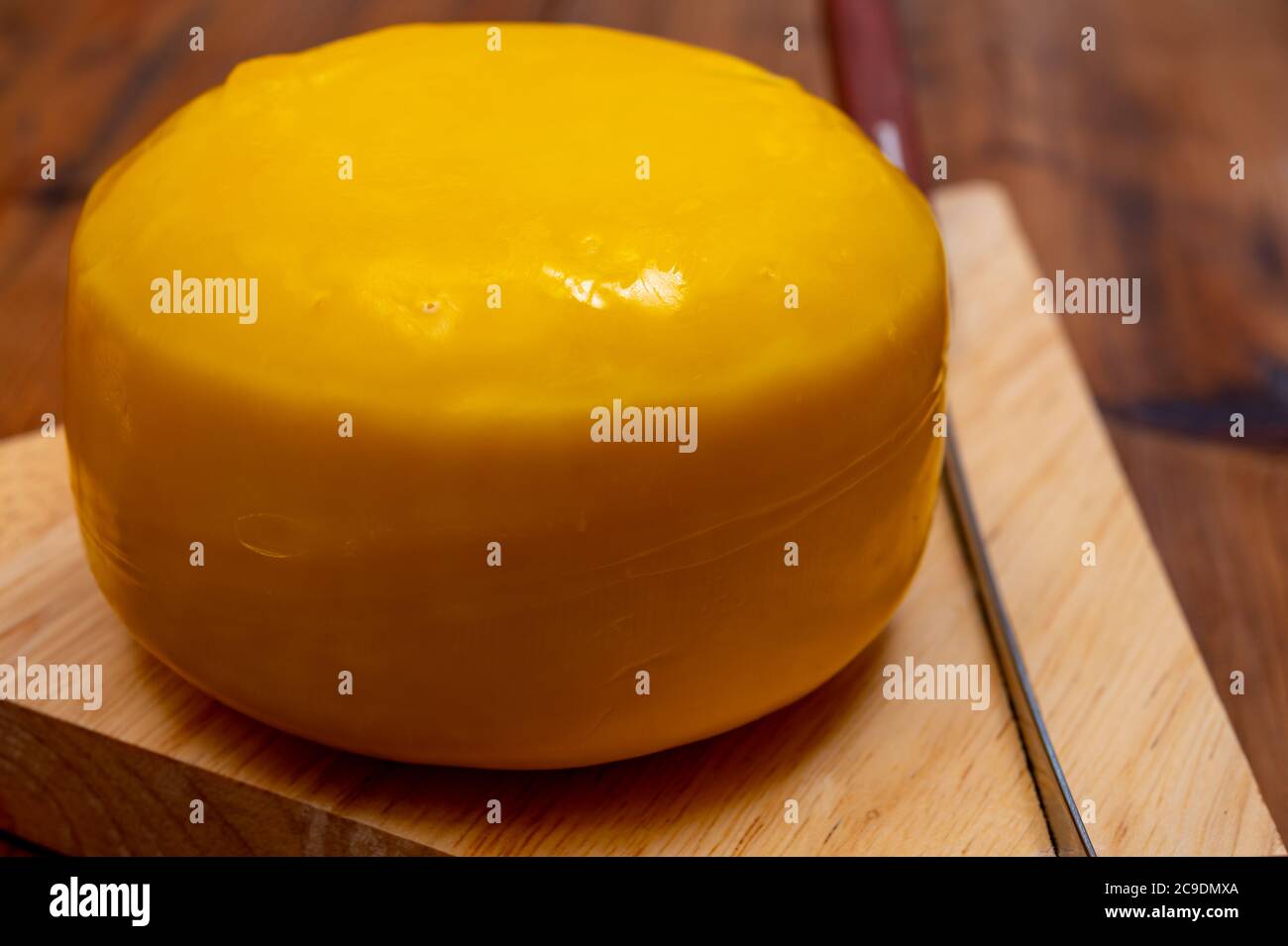 One small head of Dutch baby gouda cheese in yellow wax close up Stock ...