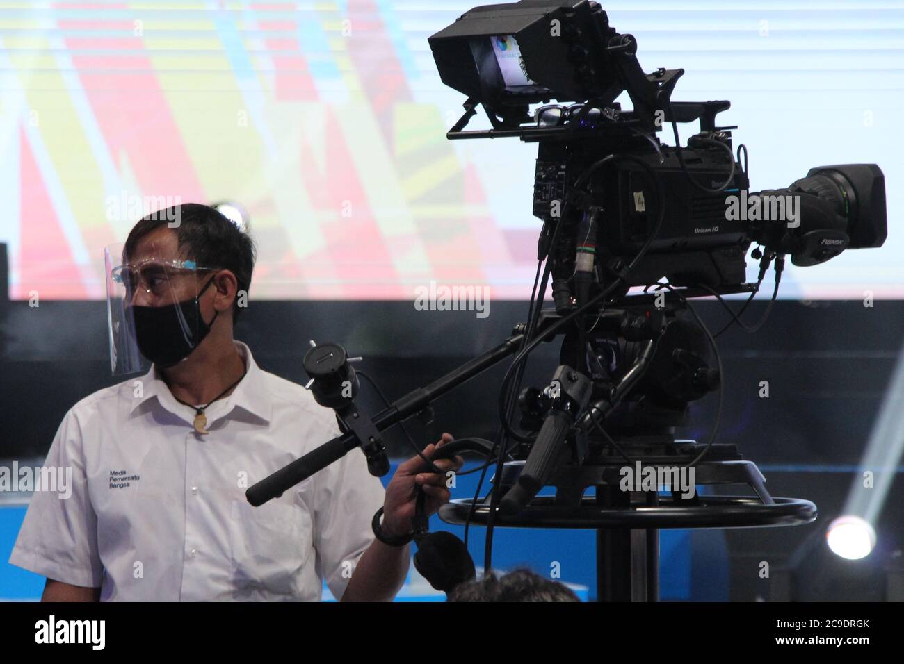 A cameraman wearing a mask and face shield applying health protocols ...