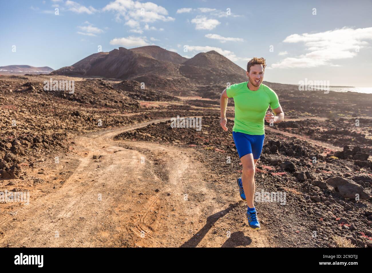 Trail runner male athlete running in nature rocky volcanic mountain ...