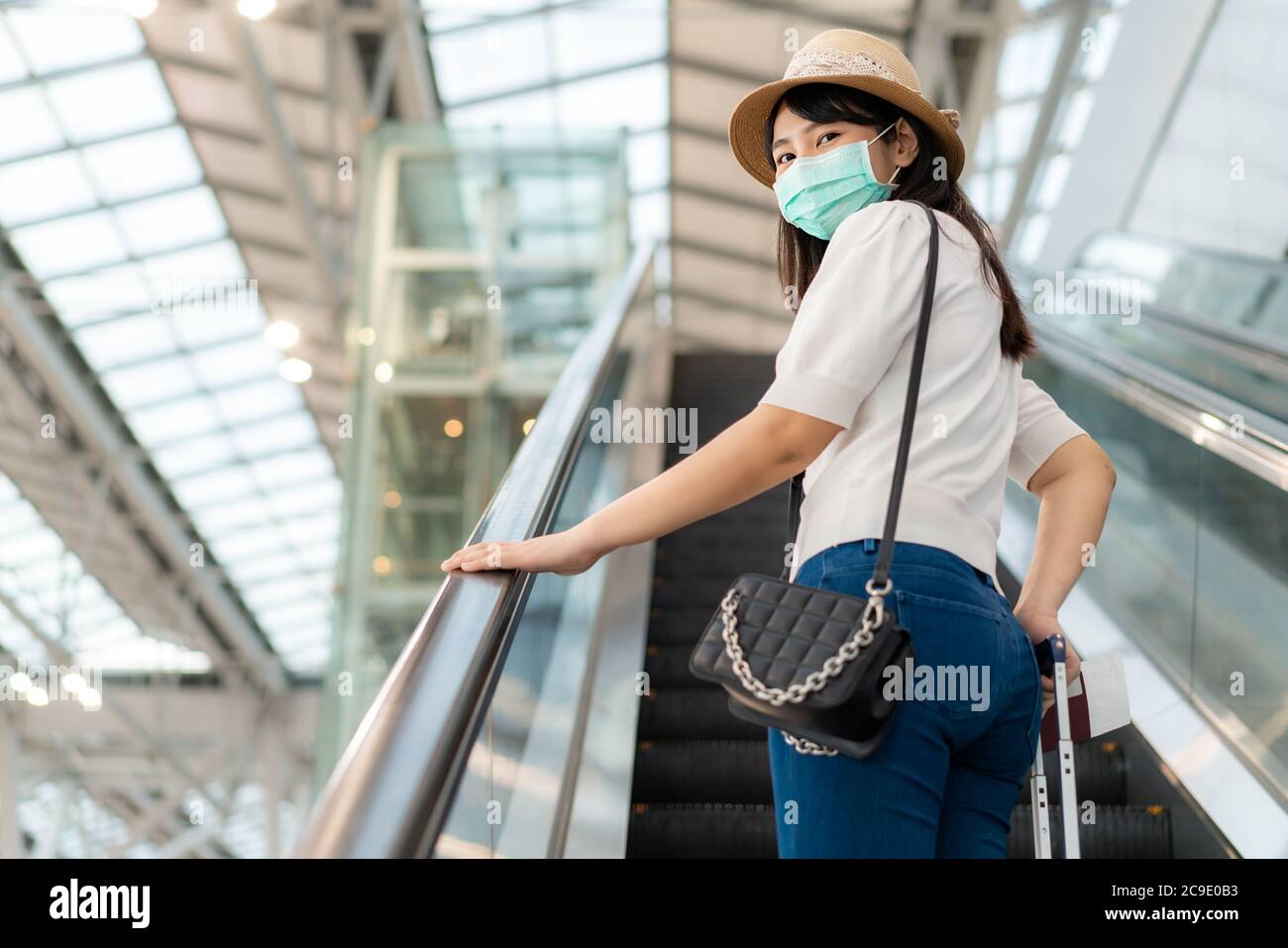 Asian traveler woman with luggage wearing face mask looking outside ...