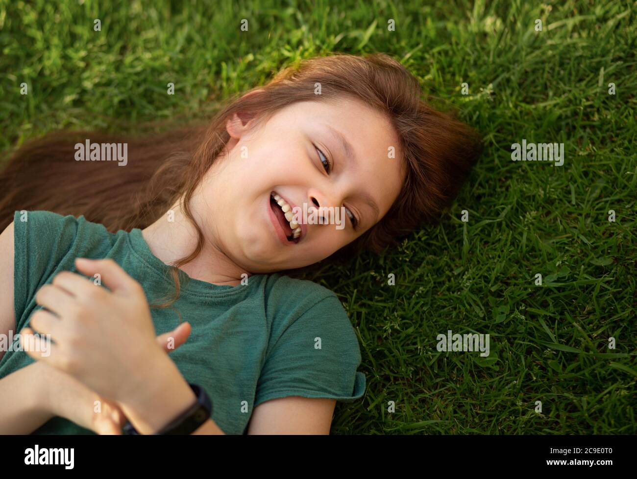 Laughing playful kid girl lying on the grass on nature summer ...