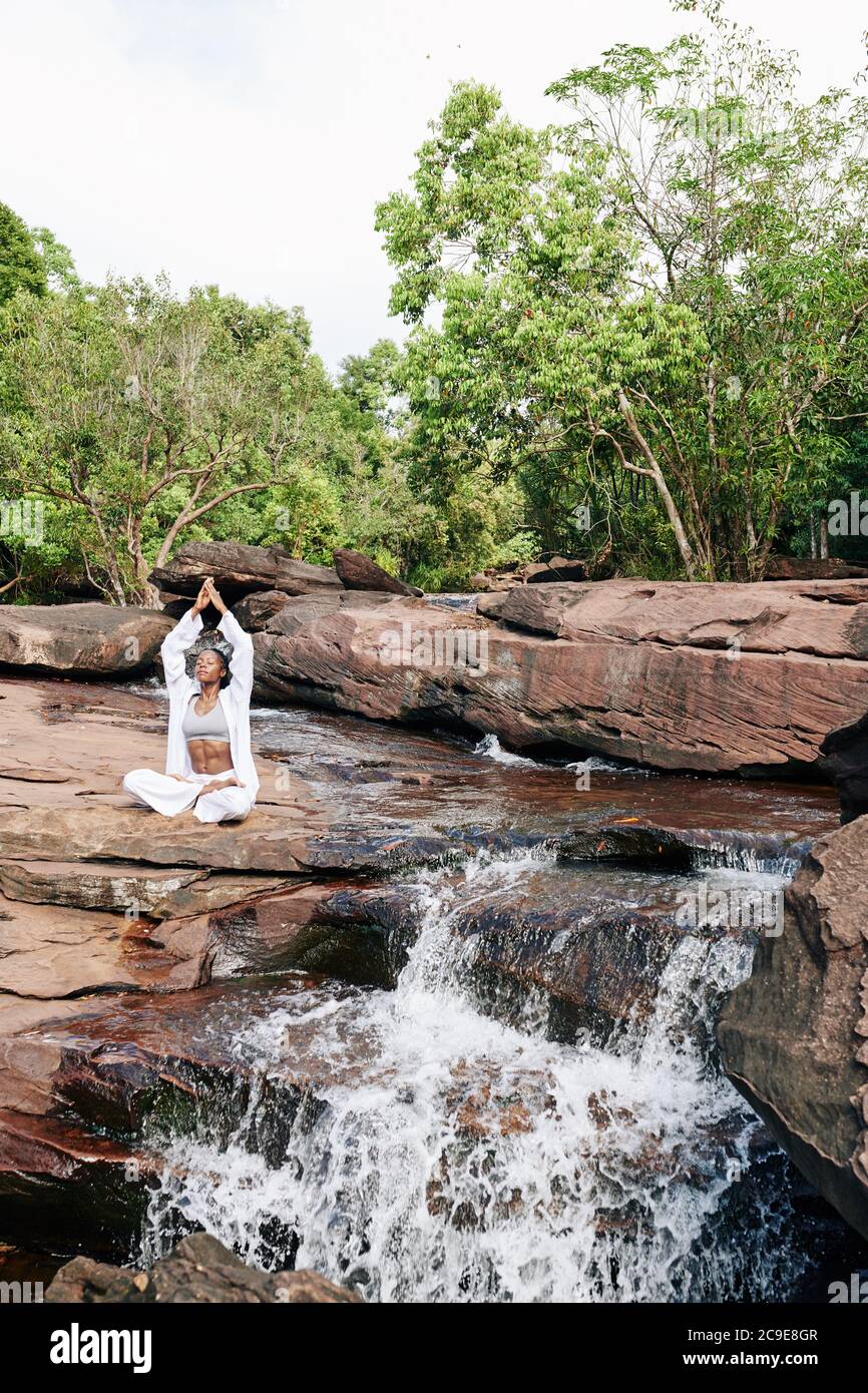 Calm meditating woman raising arms and inhaling fresh air when sitting ...