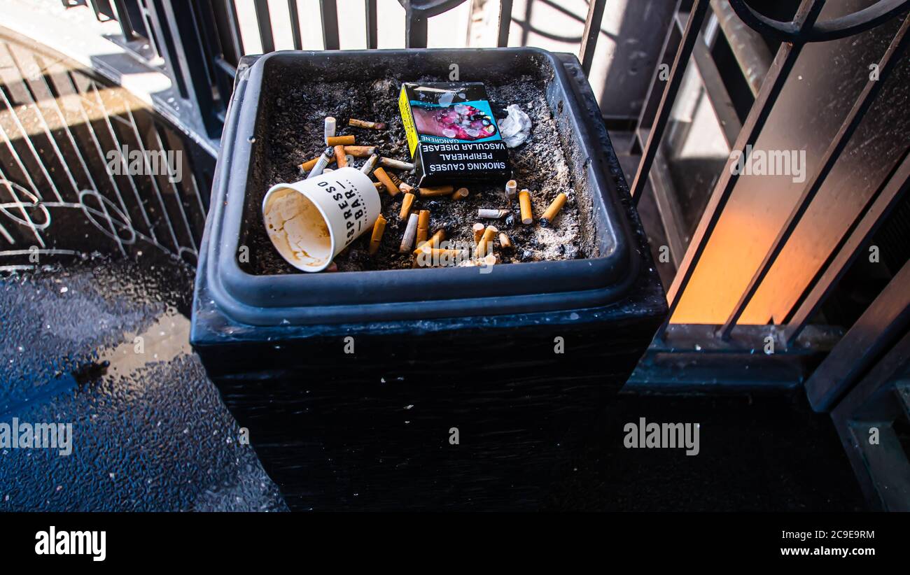 Urban public rubbish bin overflowing with cigarette buts Stock Photo ...