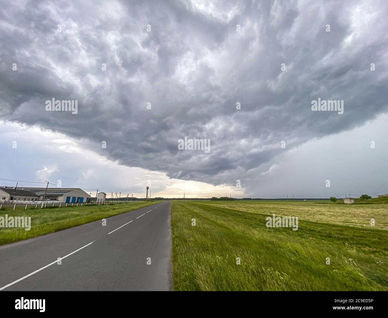 empty asphalt road through the countryside farmland with dark and ...
