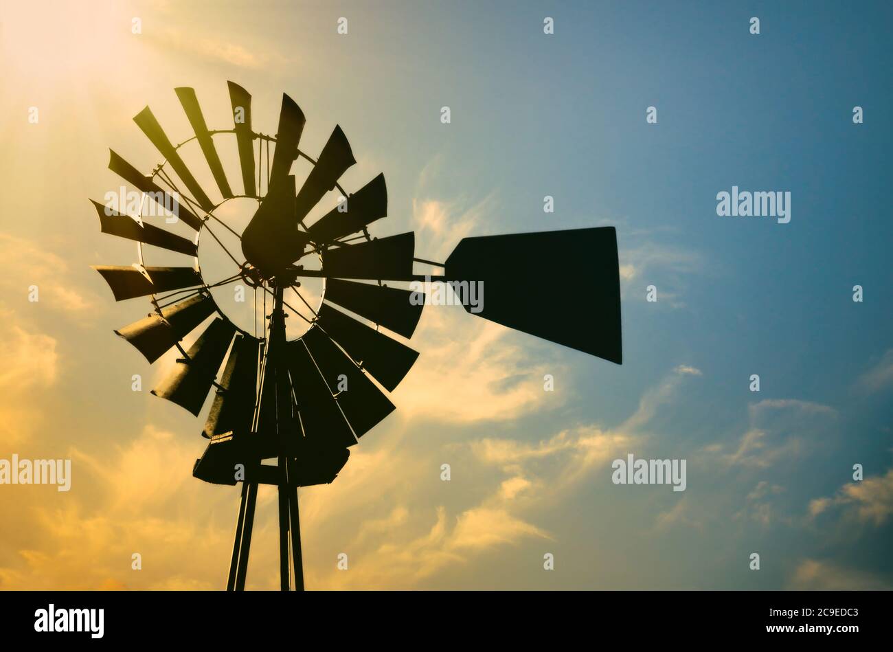 Vintage windmill silhouette against golden glowing morning sun in rural ...