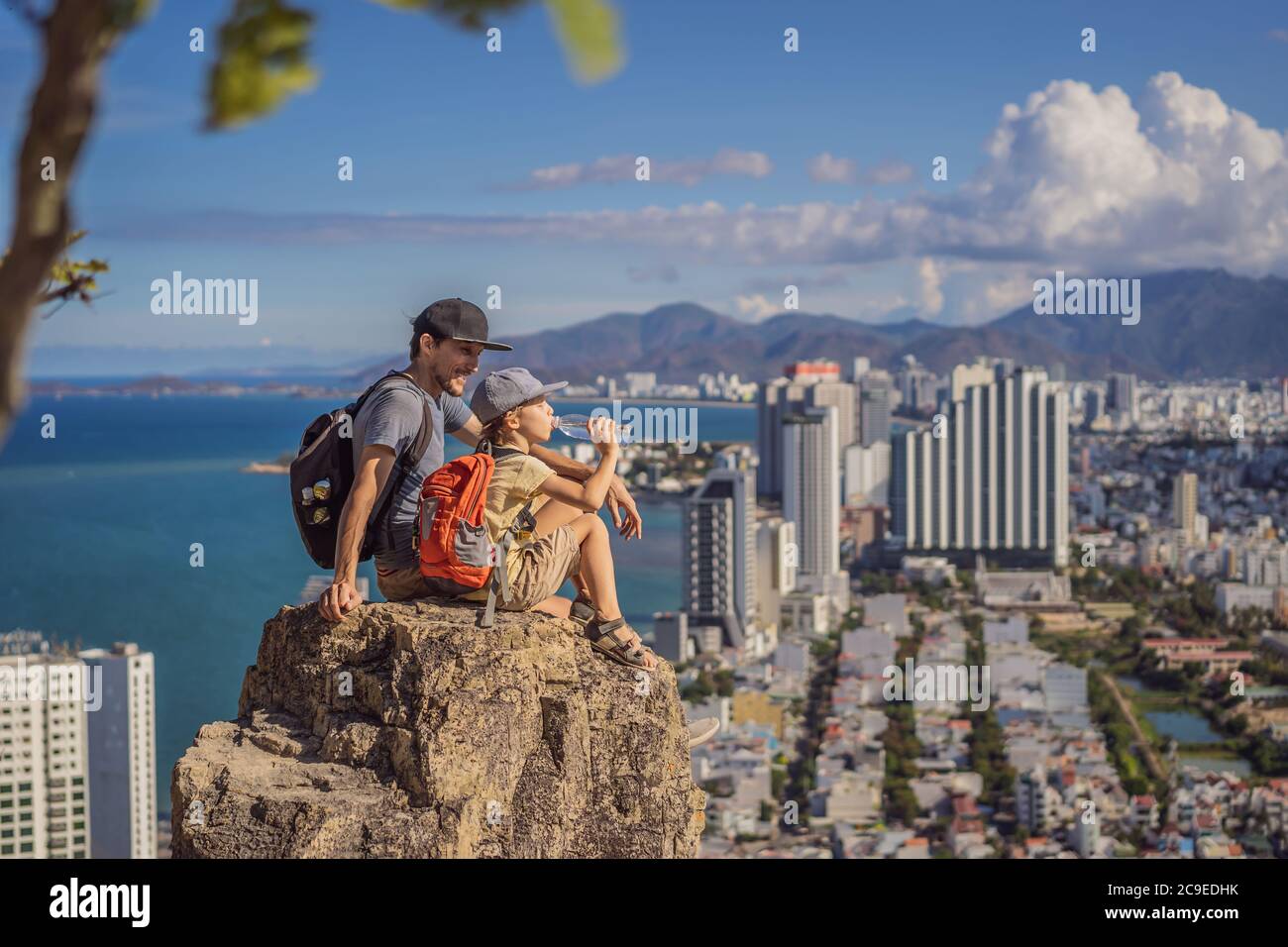 Father and son local tourist sits on a rock and enjoys the view of her ...