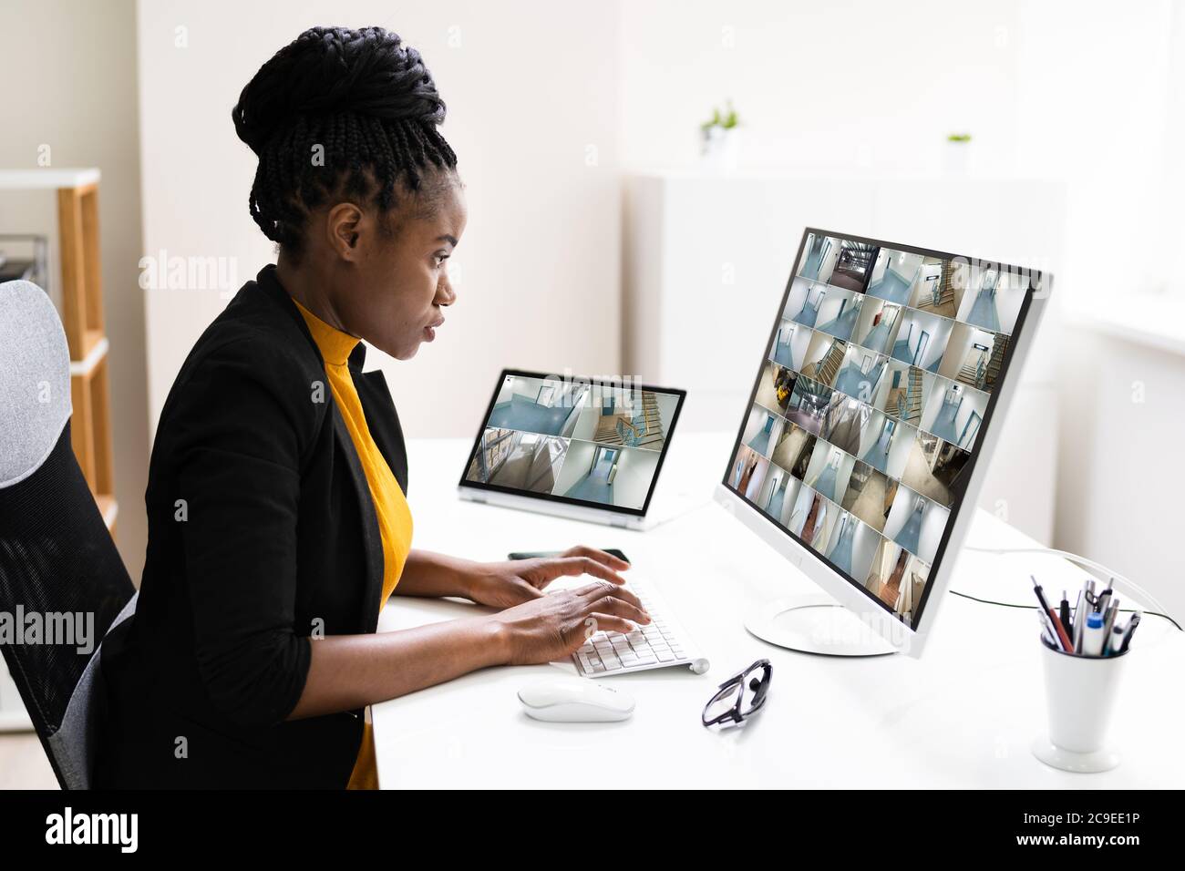 Businesswoman Watching CCTV Footage Of Office Interior On Computer At ...