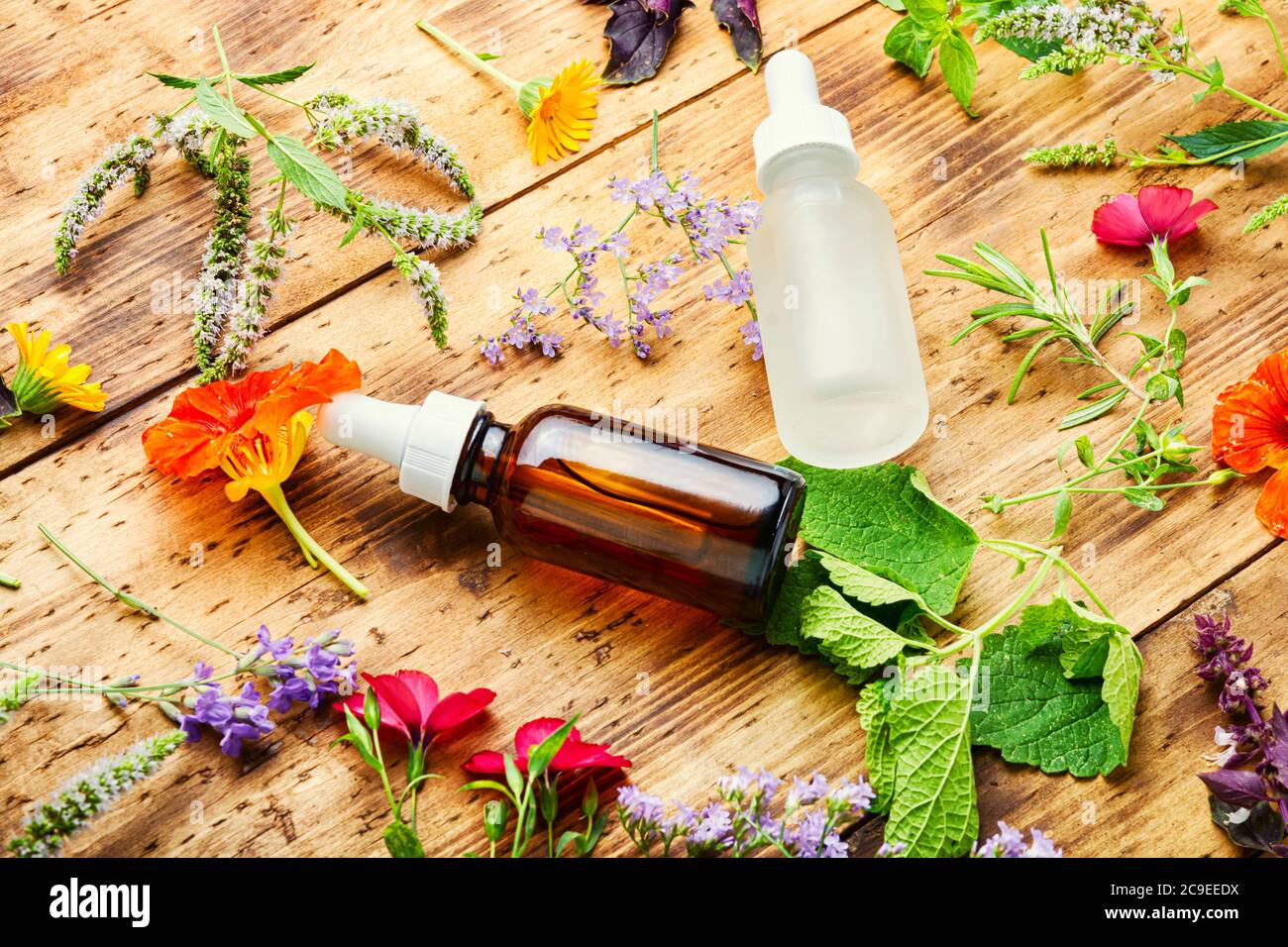 Bottles of essential oil with fresh herbs and flowers.Alternative ...
