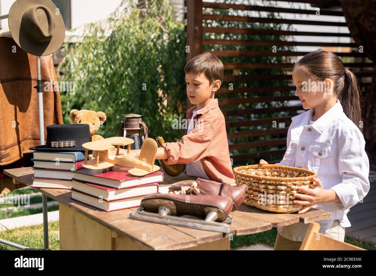Kids standing at table with books and old toys and putting it on sale ...