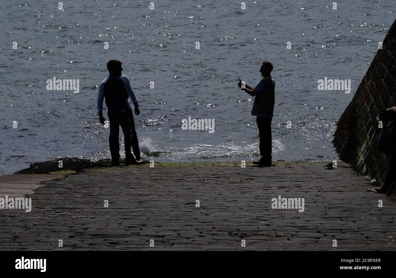Silhouette of two people on ramp into sea posing for photographs Stock ...