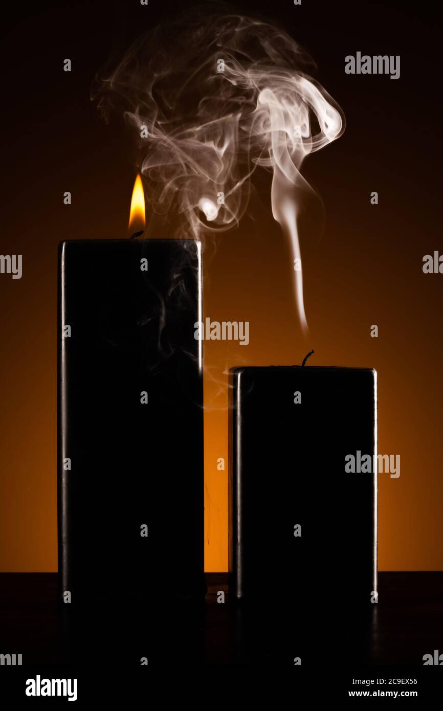 Burning black candle on dark Stock Photo - Alamy