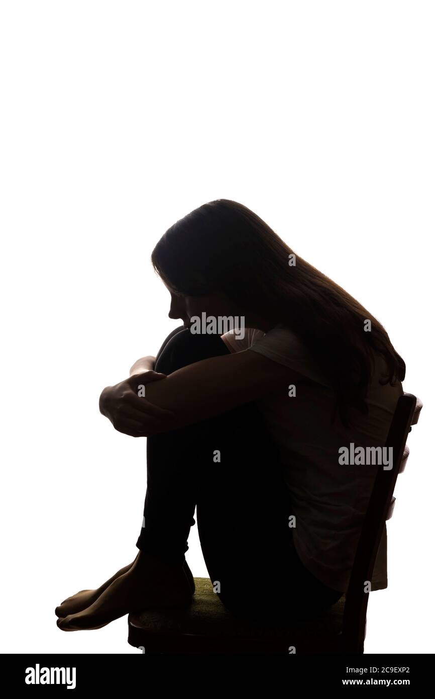 Young beautiful girl in grief hugged her knees and dropped her hands ...