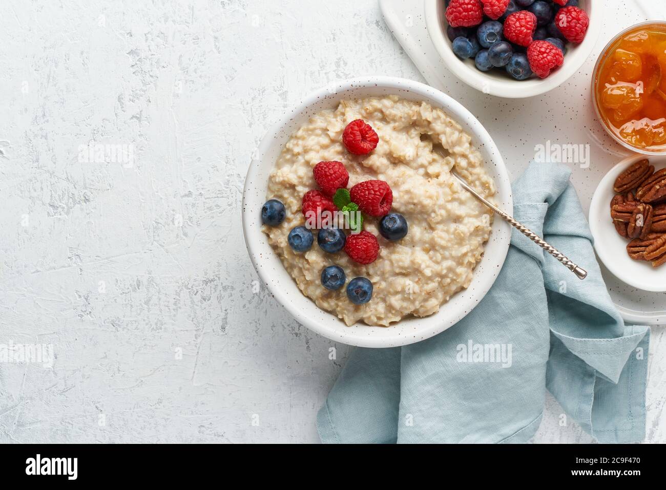 Oatmeal rustic porridge with blueberry, raspberries, jam and nuts in ...