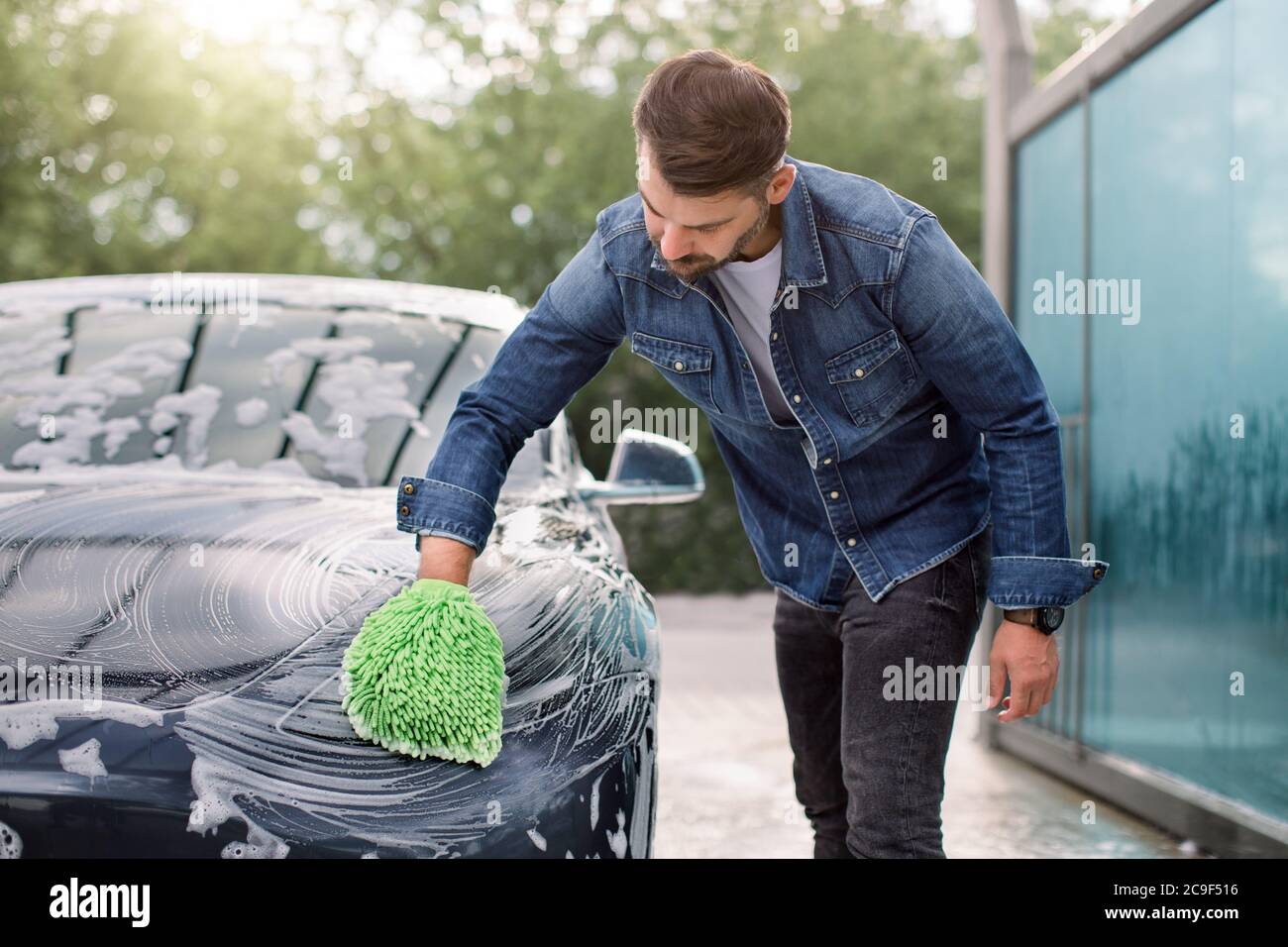 Horizontal view of car cleaning at self wash service outdoors. Handsome ...