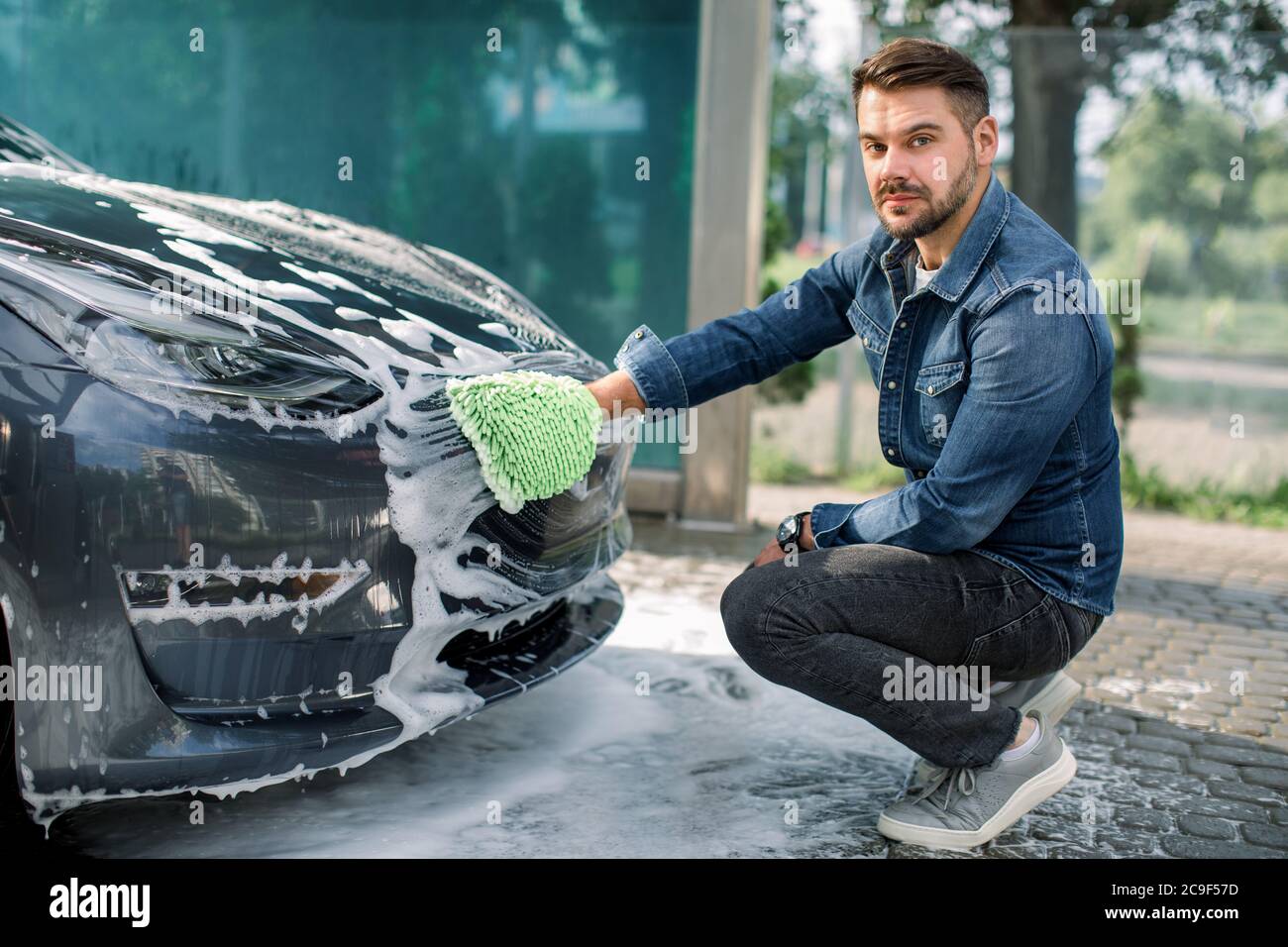 Close up photo of young Caucasian man cleaning hood of luxury electric ...