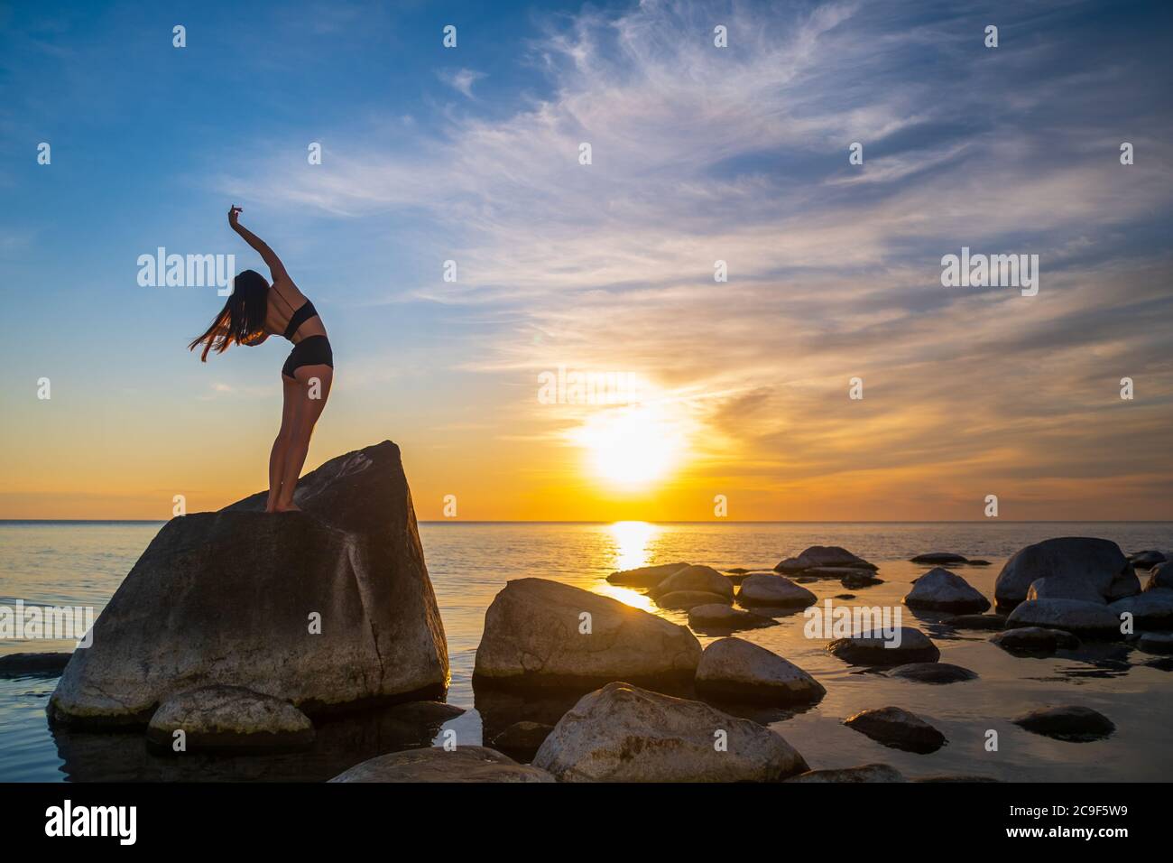 Anonymous female dancing on rock near sea Stock Photo - Alamy