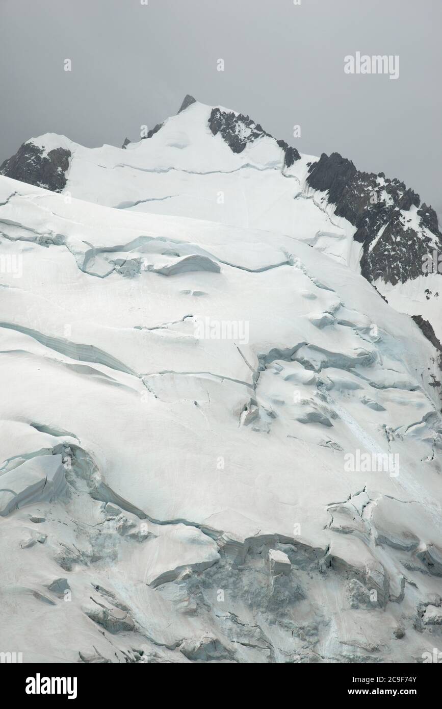 Deep snow drifts on the side of a mountain. Dark rock visible in places ...