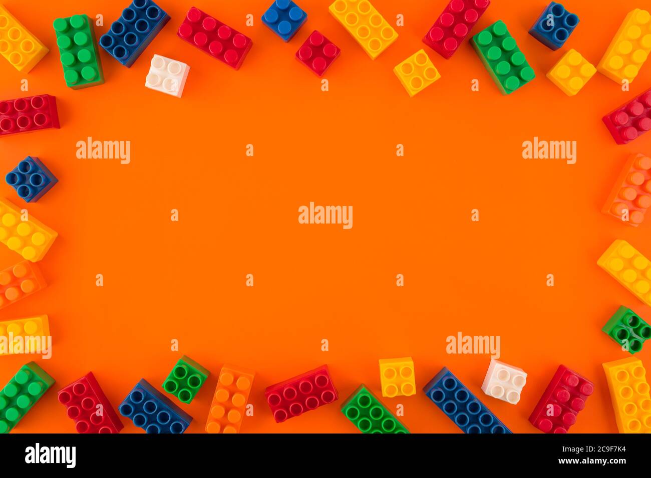 Pile toy colored plastic blocks and colored toy bricks on orange ...