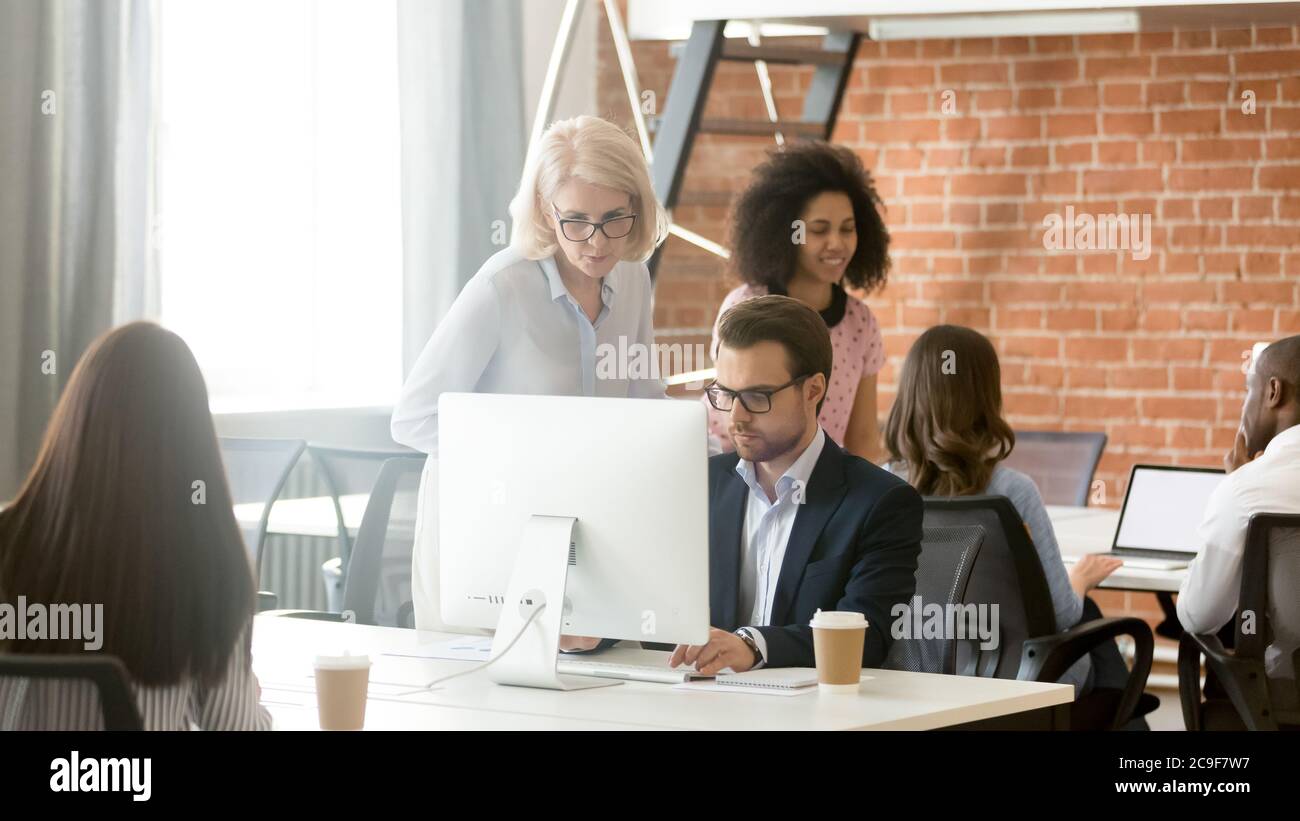 Mature businesswoman mentor helping employee with corporate software ...