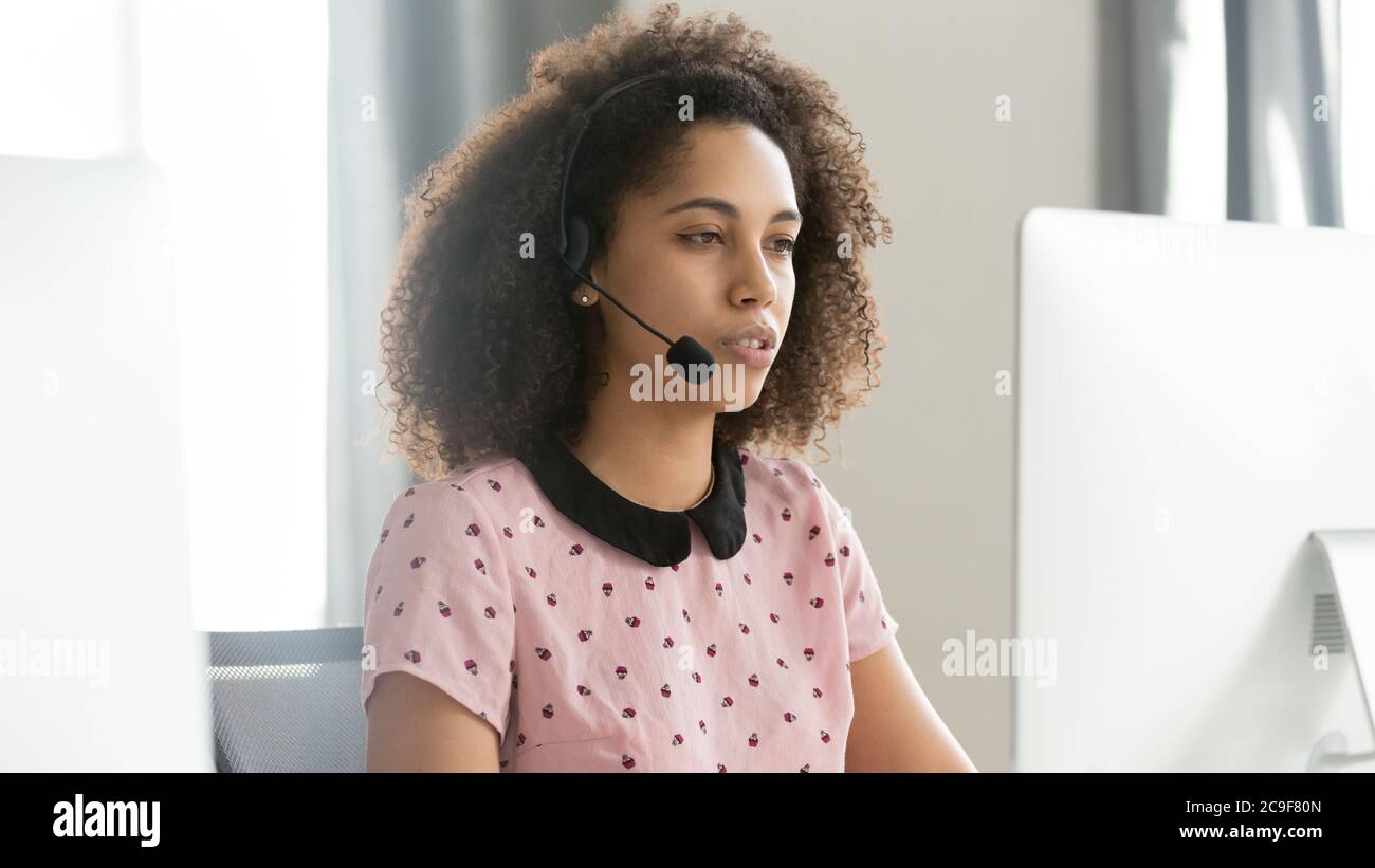 African American female call center operator in headset using computer ...