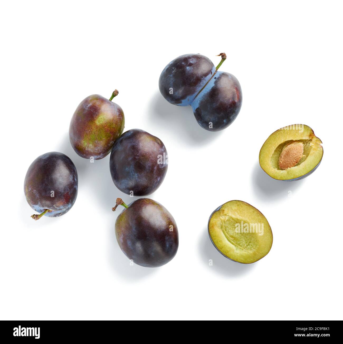 ripe whole blue plum, broken in half with a bone. Fruit isolated on ...