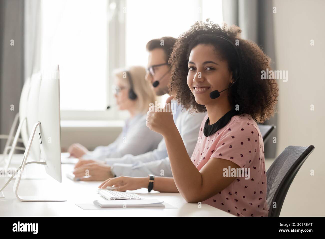 Smiling female call center operator in headset showing thumbs up Stock ...