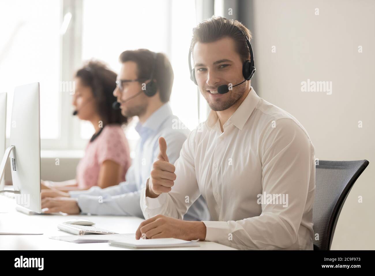 Smiling customer support service operator in headset showing thumbs up ...