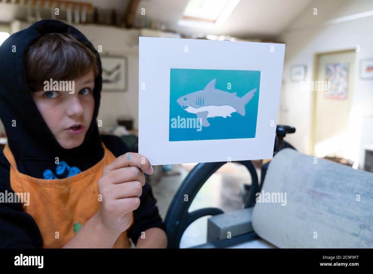 Boy showing linocut print of shark made in printmaking etching press ...