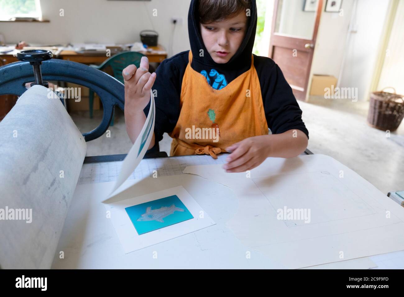 Boy looking at linocut artwork on a etching press he has made in a ...