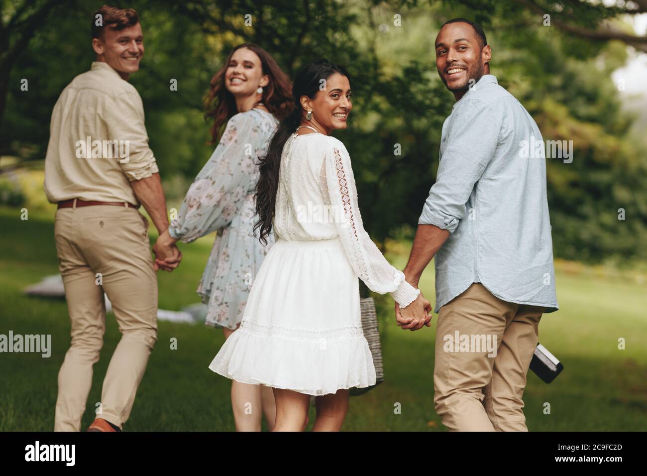Rear view of group of young people walking in the park. Cheerful ...