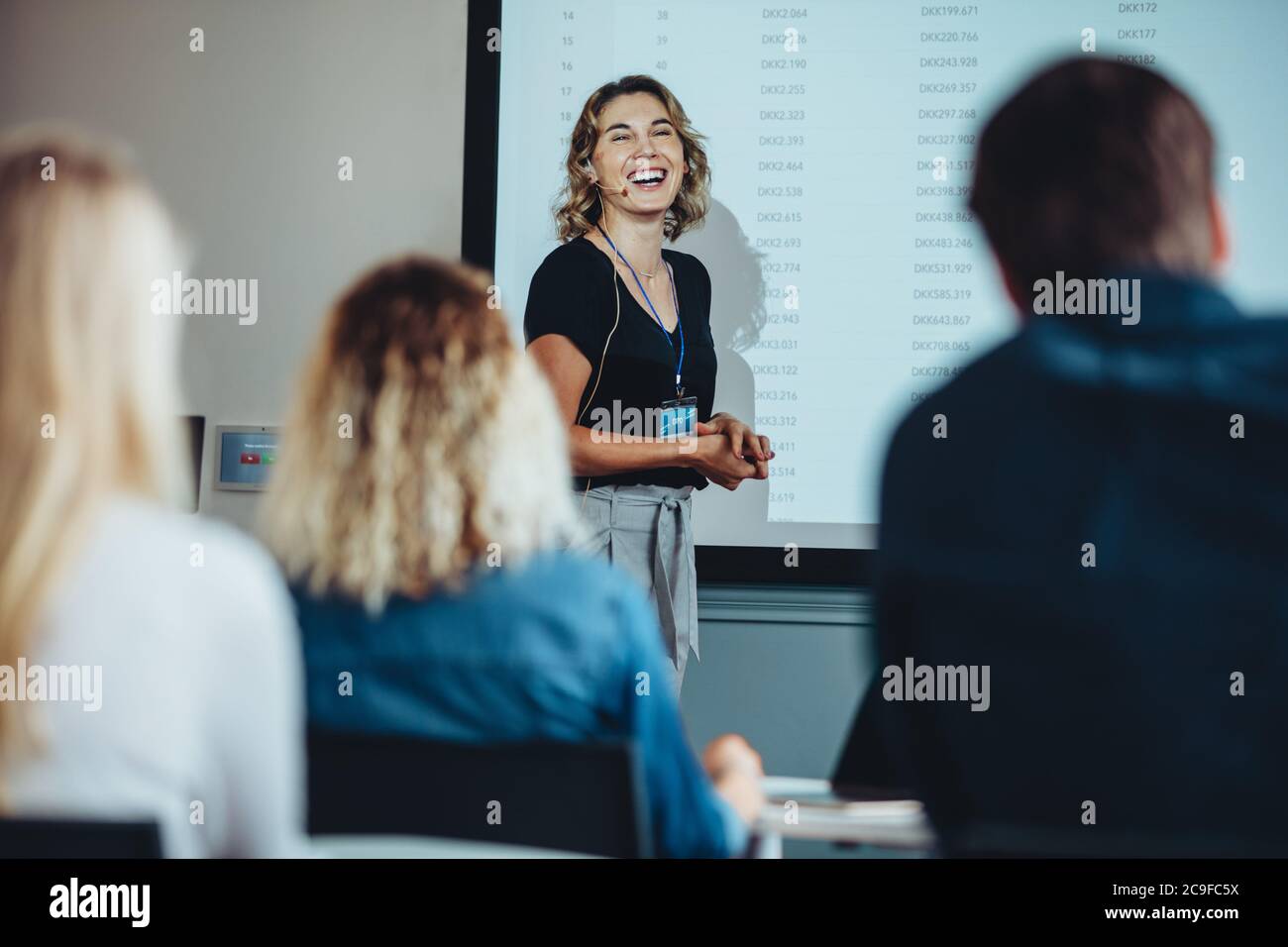 Businesswoman standing at projector screen and smiling during a ...